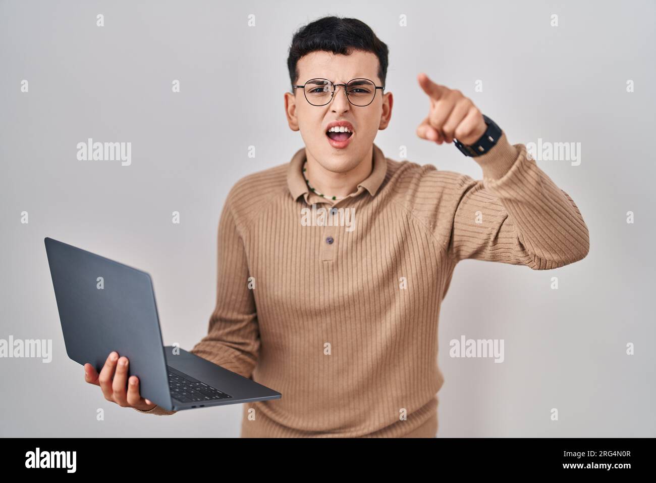 Non binary person using computer laptop pointing displeased and ...