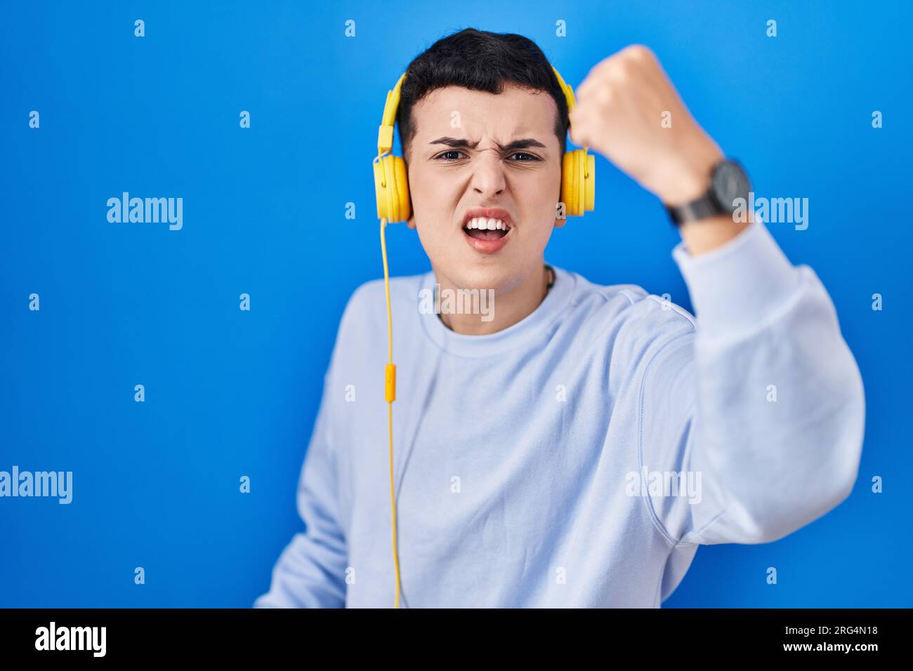 Non binary person listening to music using headphones angry and mad ...