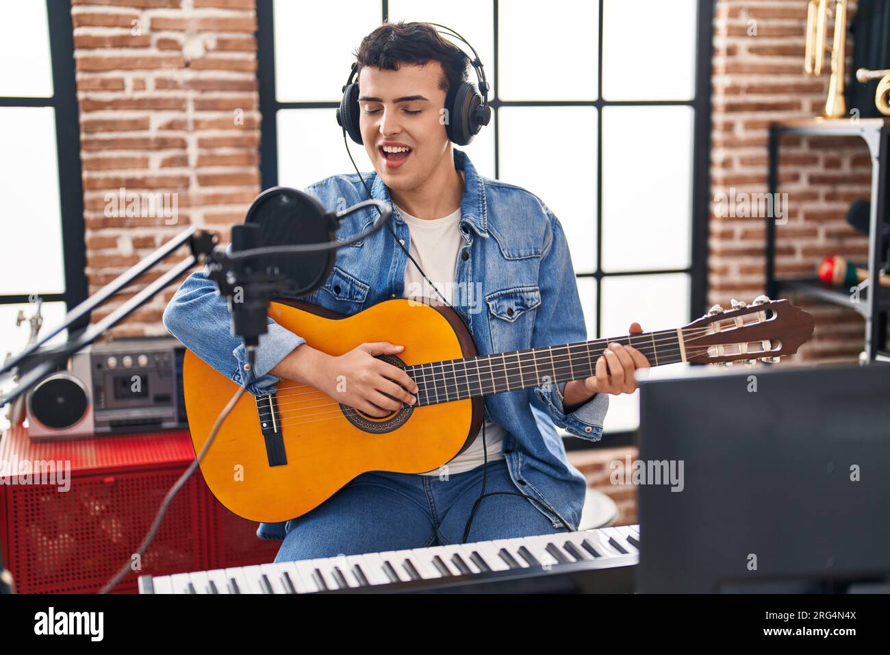 Young non binary man musician singing song playing classical guitar at ...