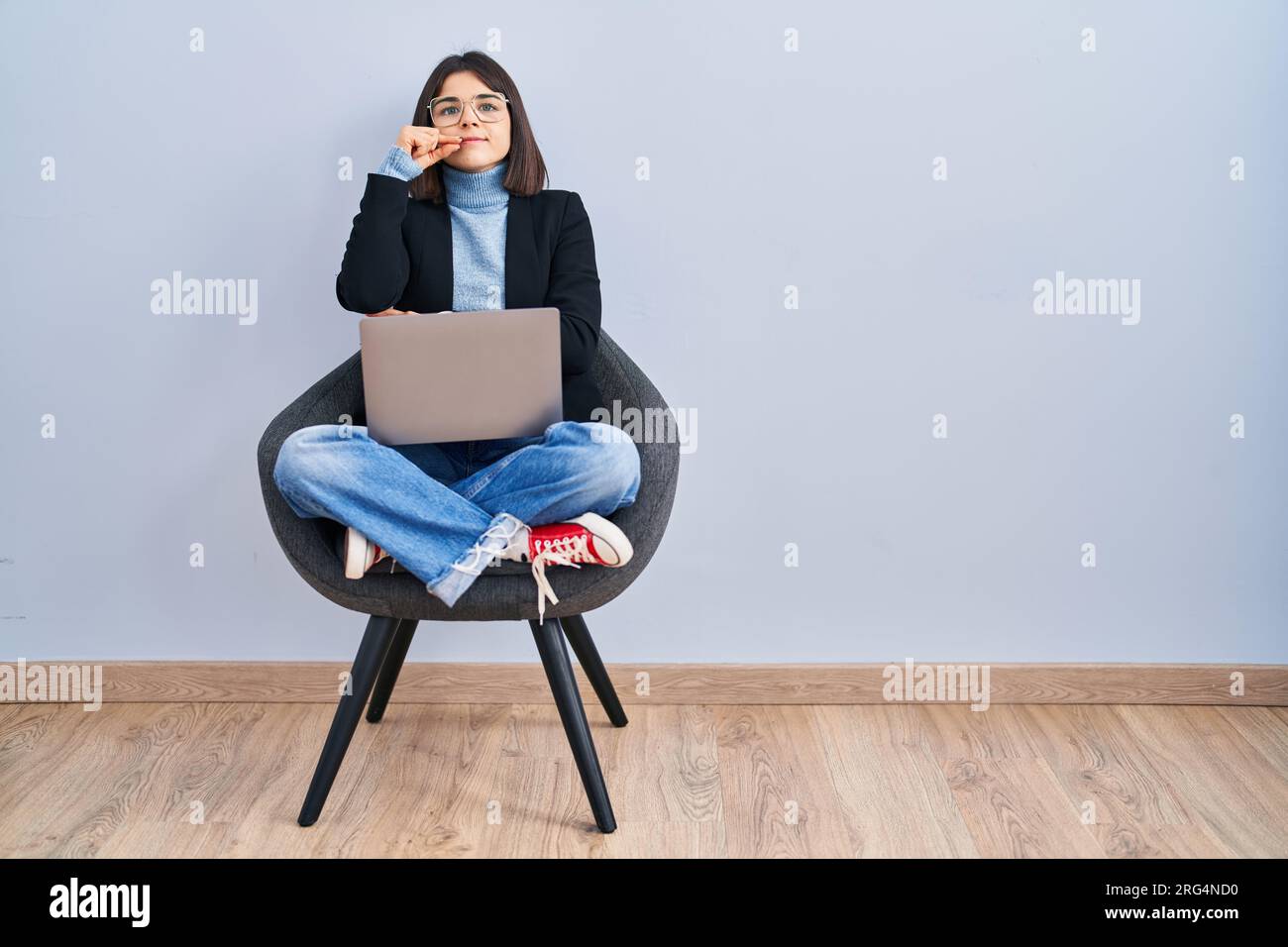 Young hispanic woman sitting on chair using computer laptop mouth and ...