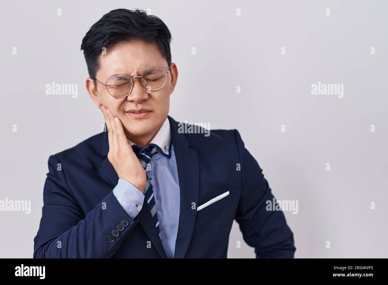 Young asian man wearing business suit and tie touching mouth with hand ...