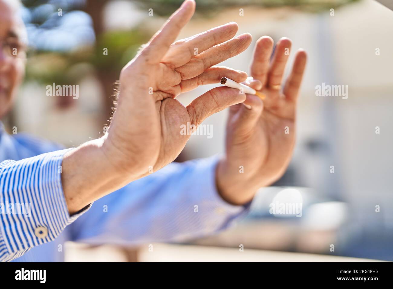 Senior man breaking cigarette at park Stock Photo - Alamy