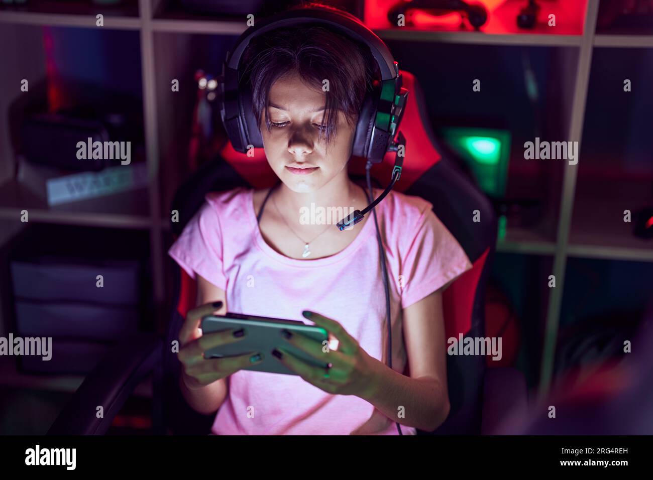 Adorable hispanic girl streamer playing video game using smartphone at ...