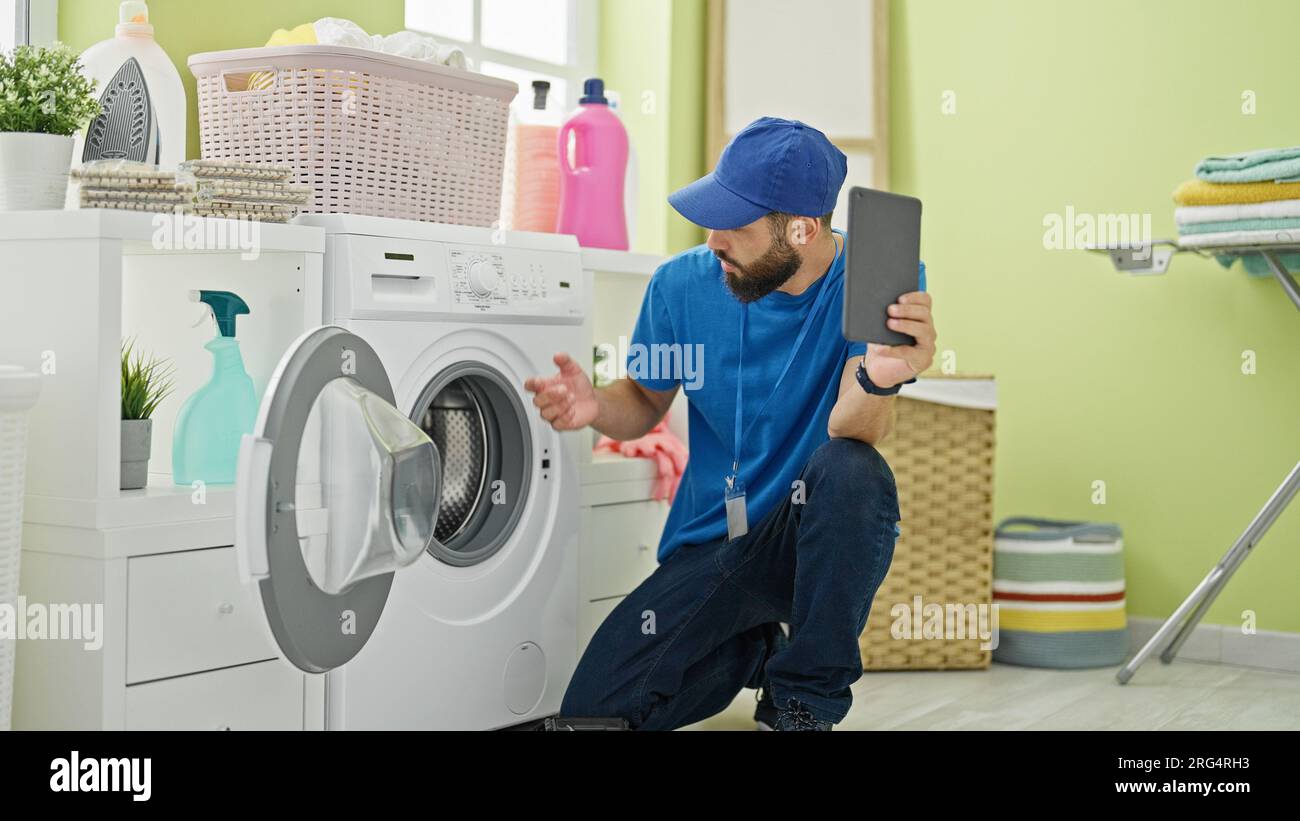 Young hispanic man technician repairing washing machine holding ...