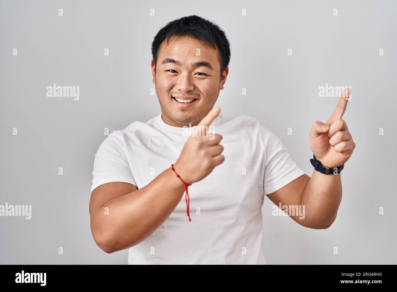 Young chinese man standing over white background smiling and looking at ...