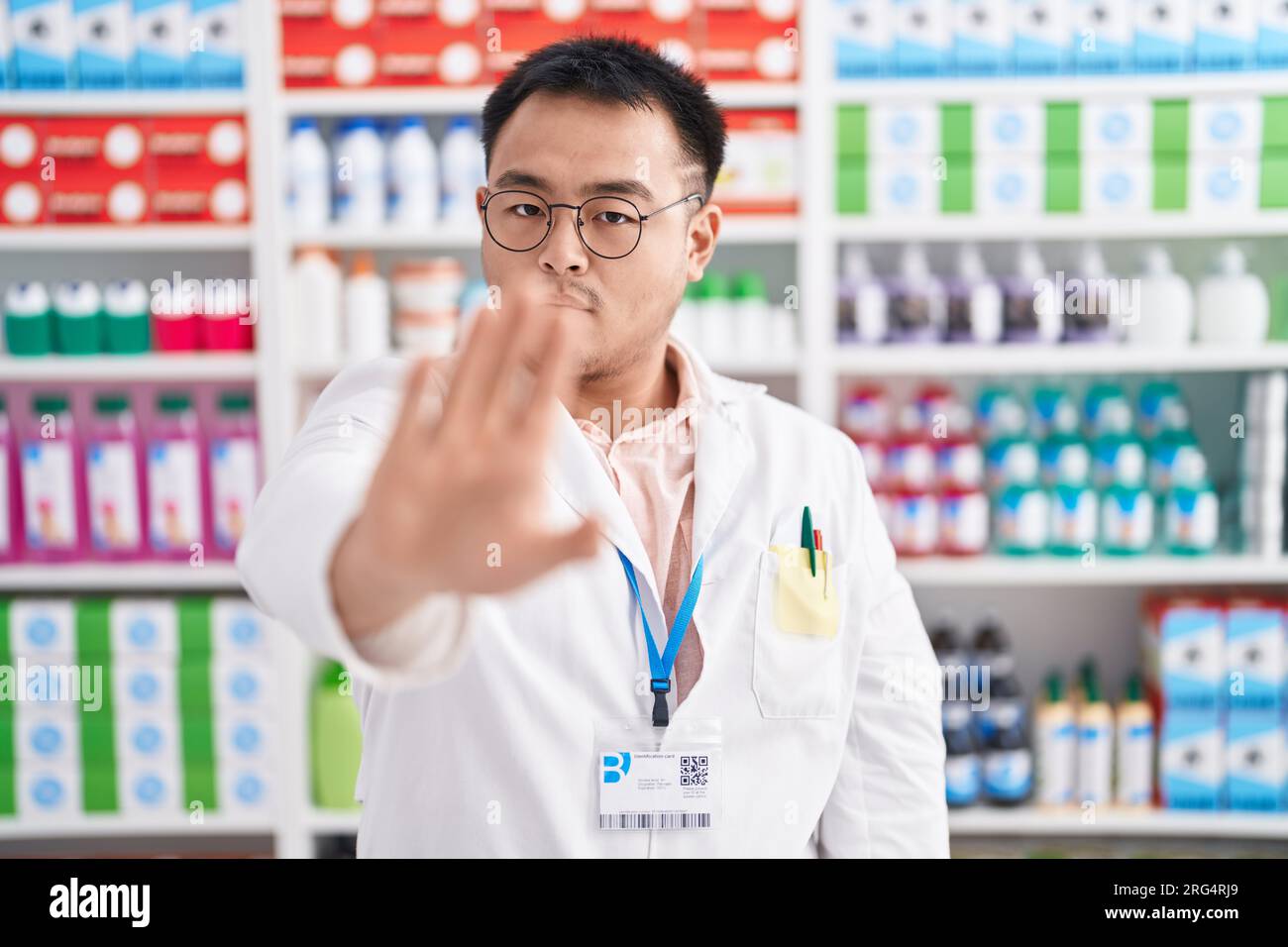 Chinese young man working at pharmacy drugstore doing stop sing with ...
