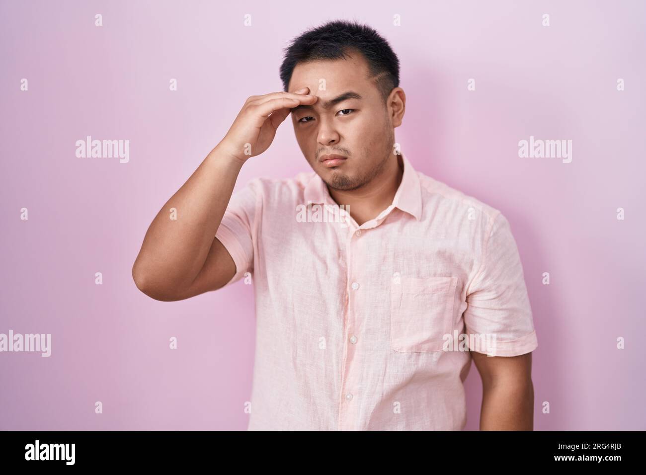 Chinese young man standing over pink background worried and stressed ...