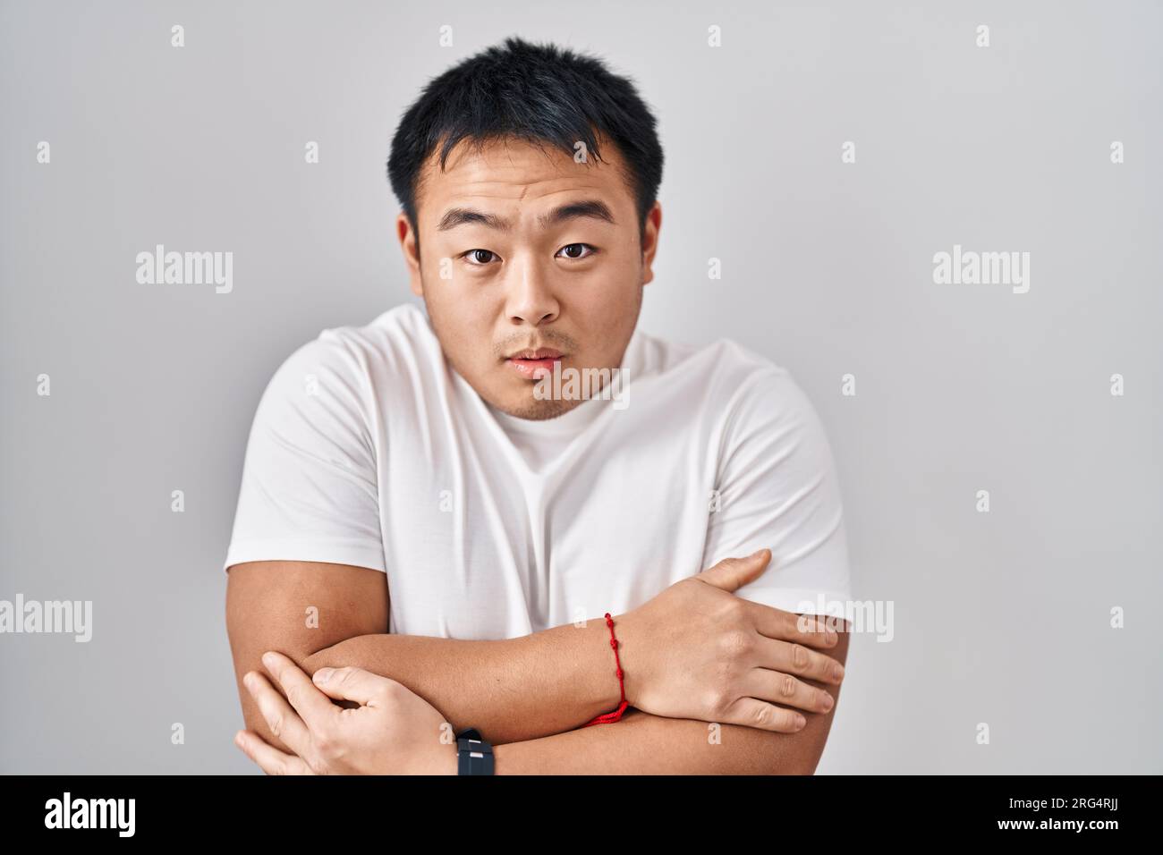 Young chinese man standing over white background shaking and freezing ...