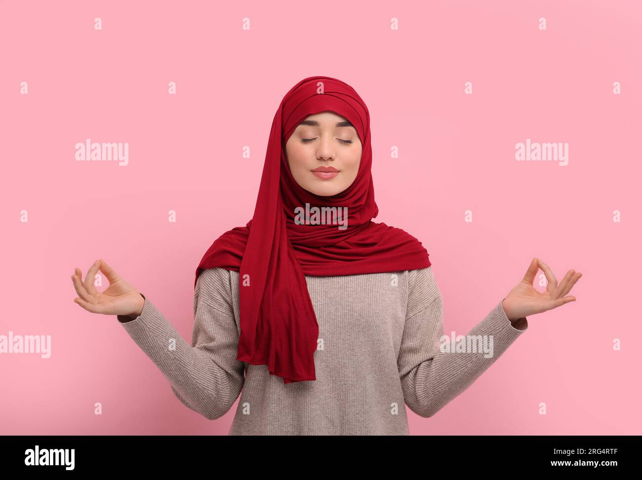 Muslim woman in hijab meditating on pink background Stock Photo - Alamy