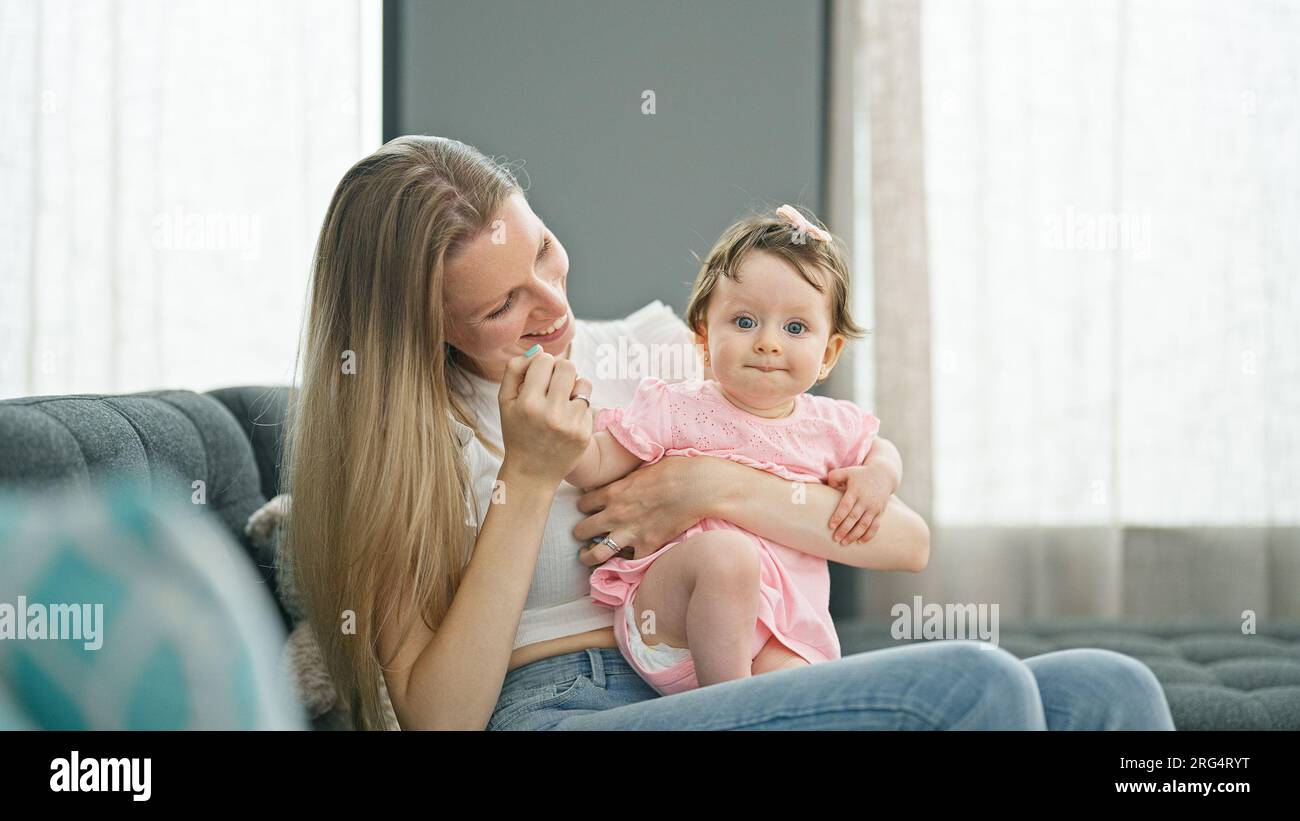 Mother and daughter hugging each other sitting on sofa at home Stock Photo - Alamy