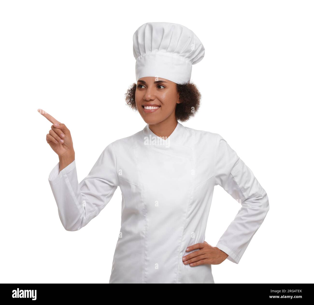 Happy female chef in uniform pointing at something on white background ...