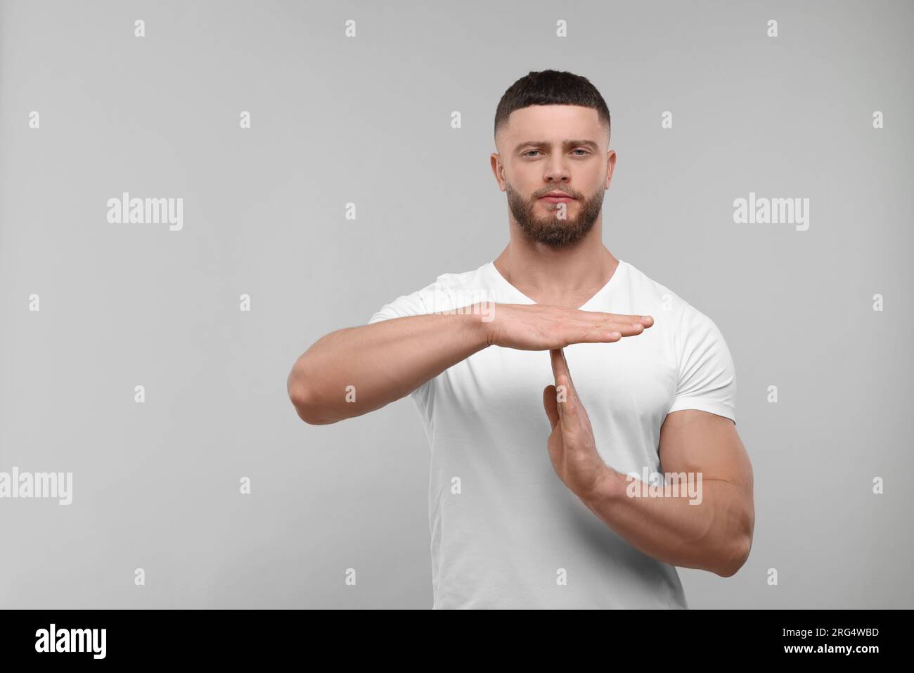 Man showing time out gesture on light grey background. Space for text ...