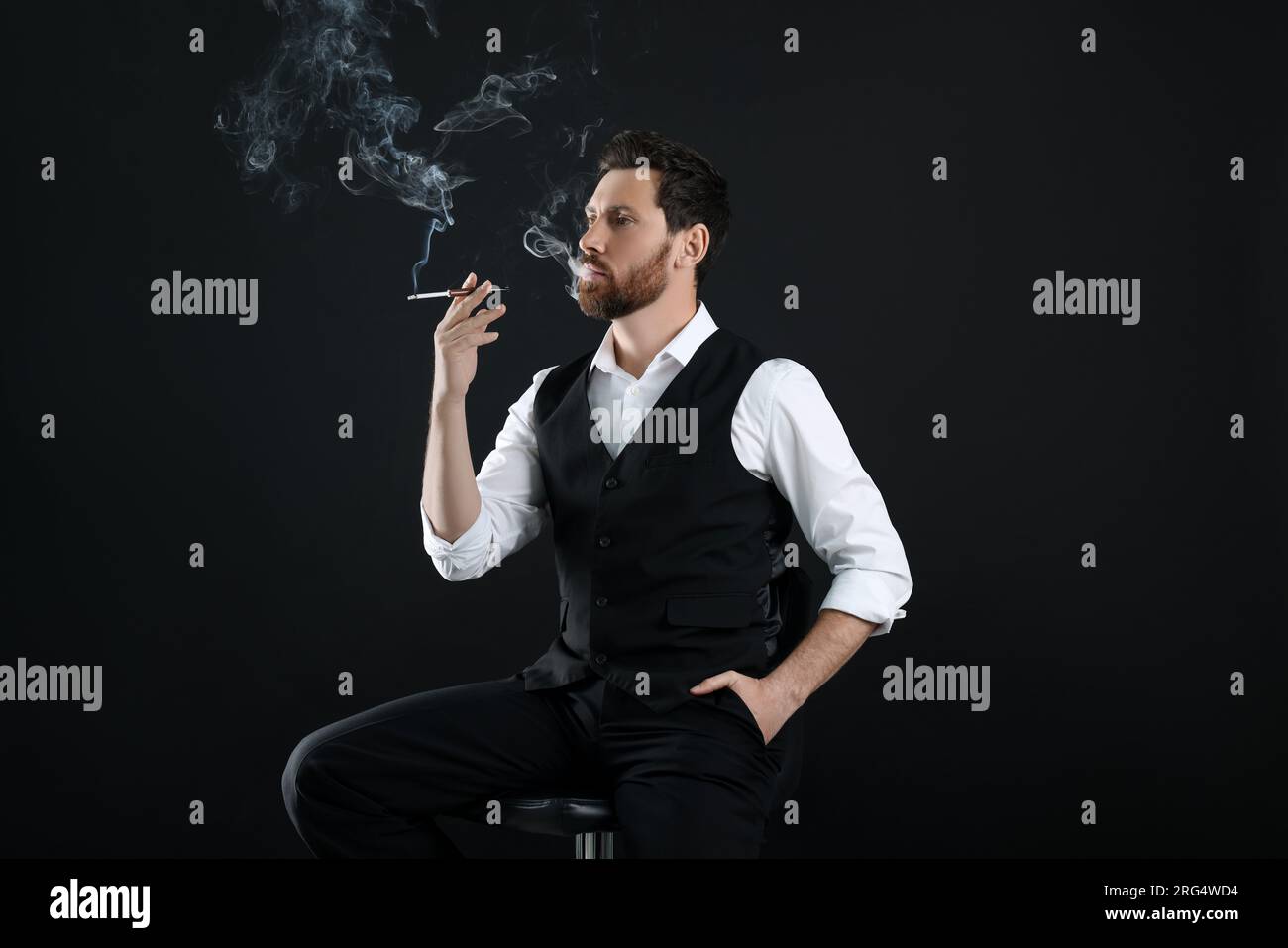 Man using cigarette holder for smoking on black background Stock Photo ...