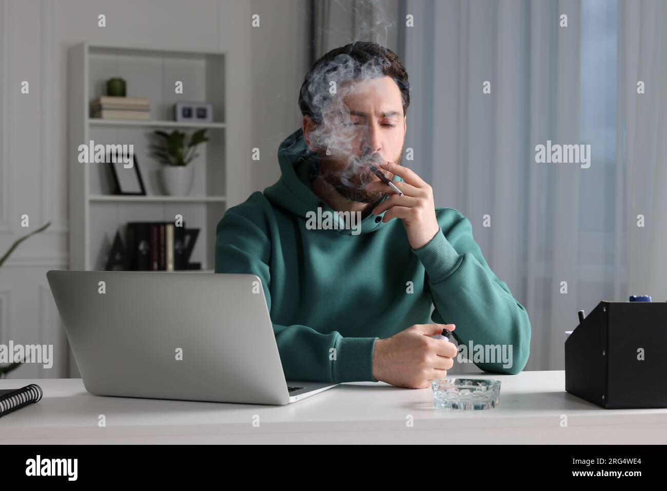 Man using cigarette holder for smoking at workplace in office Stock ...
