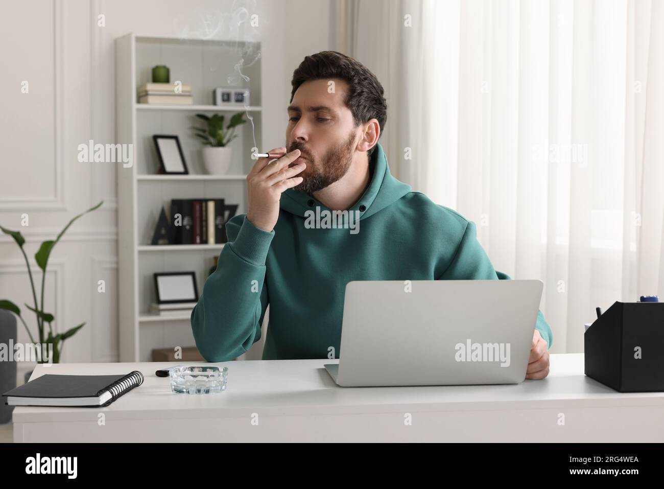 Man using cigarette holder for smoking at workplace in office Stock ...