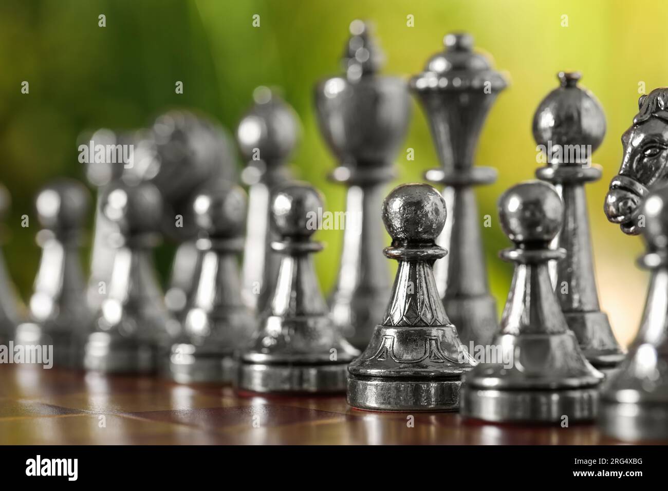 Silver chess pieces on game board against blurred background, closeup ...