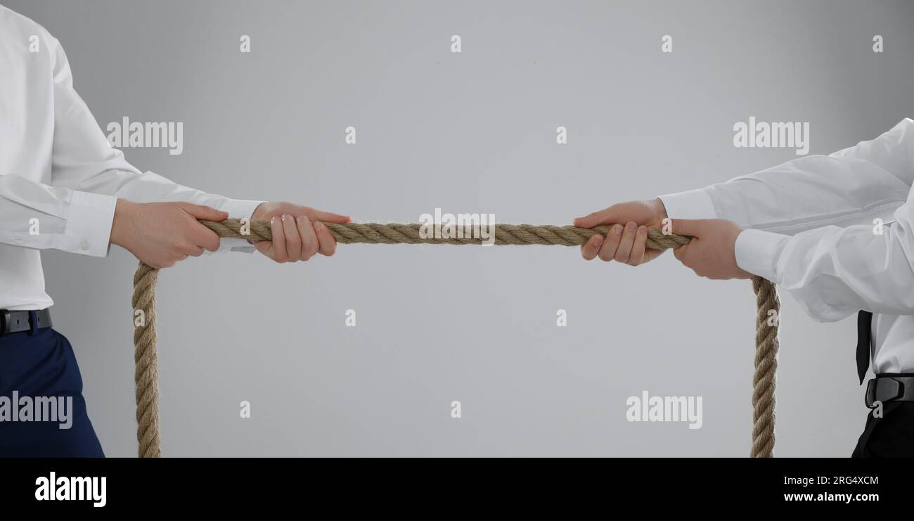 Dispute concept. Men pulling rope on light grey background, closeup ...