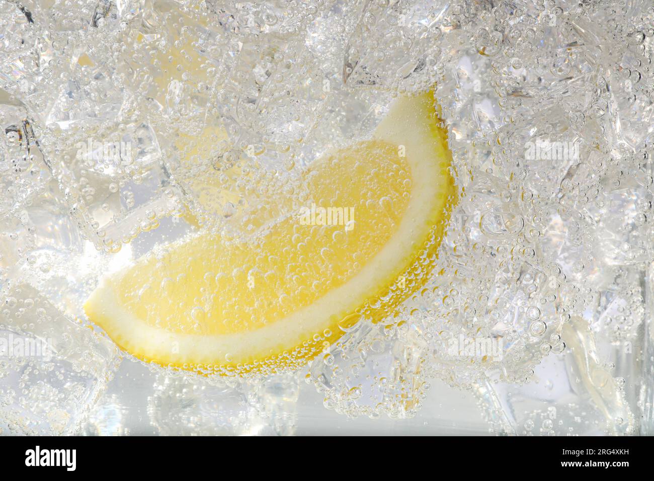 Juicy lemon slice and ice cubes in soda water on white background ...