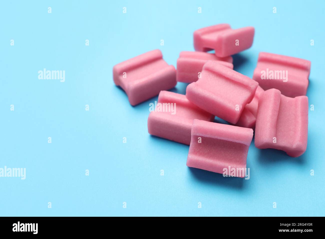 Tasty pink chewing gums on light blue background, closeup. Space for ...