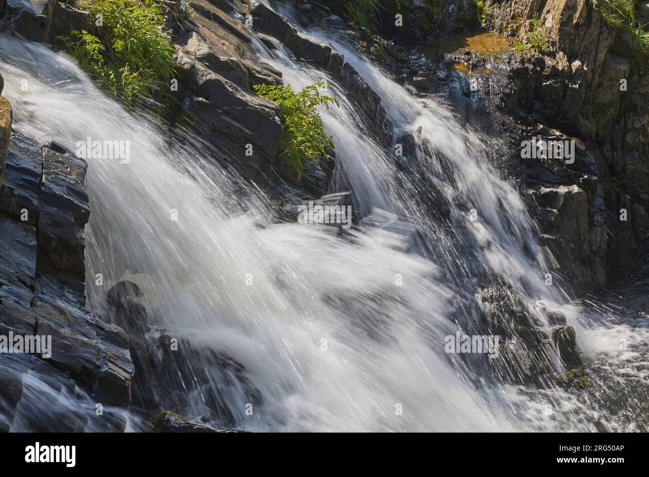 Water pouring over a waterfall in sunshine, at Welcombe Mouth, Hartland ...