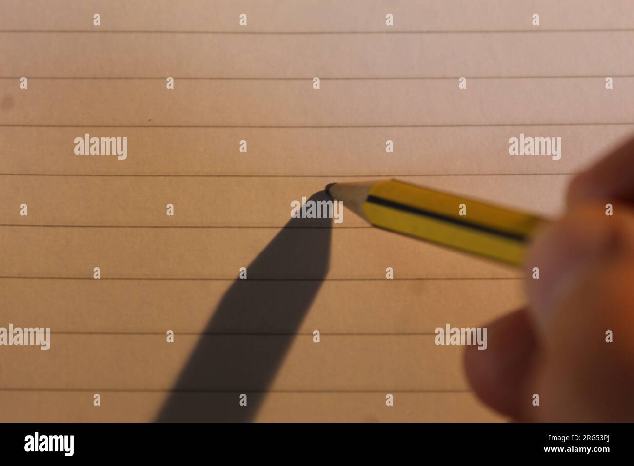 A photo of a person putting a pencil to a lined page Stock Photo - Alamy