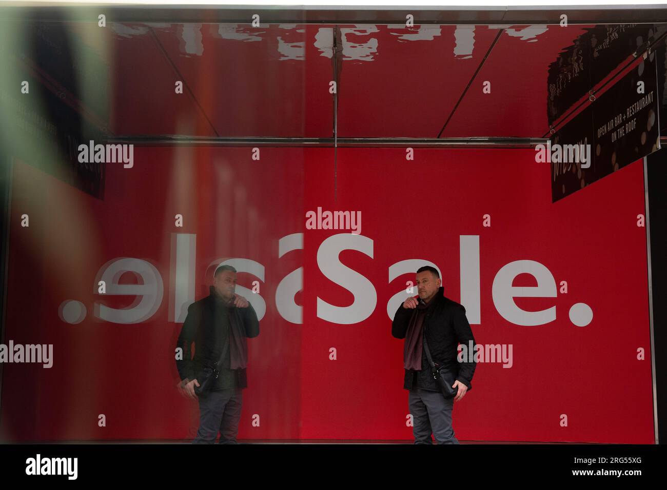 A sales signage is reflected in a bus stop wall on Oxford Street in ...