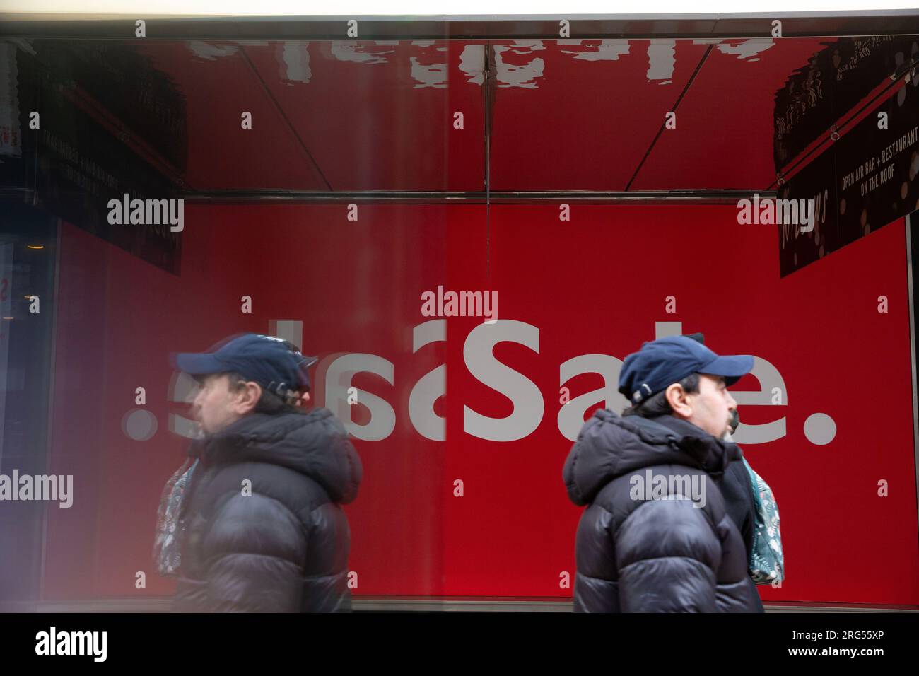A sales signage is reflected in a bus stop wall on Oxford Street in ...