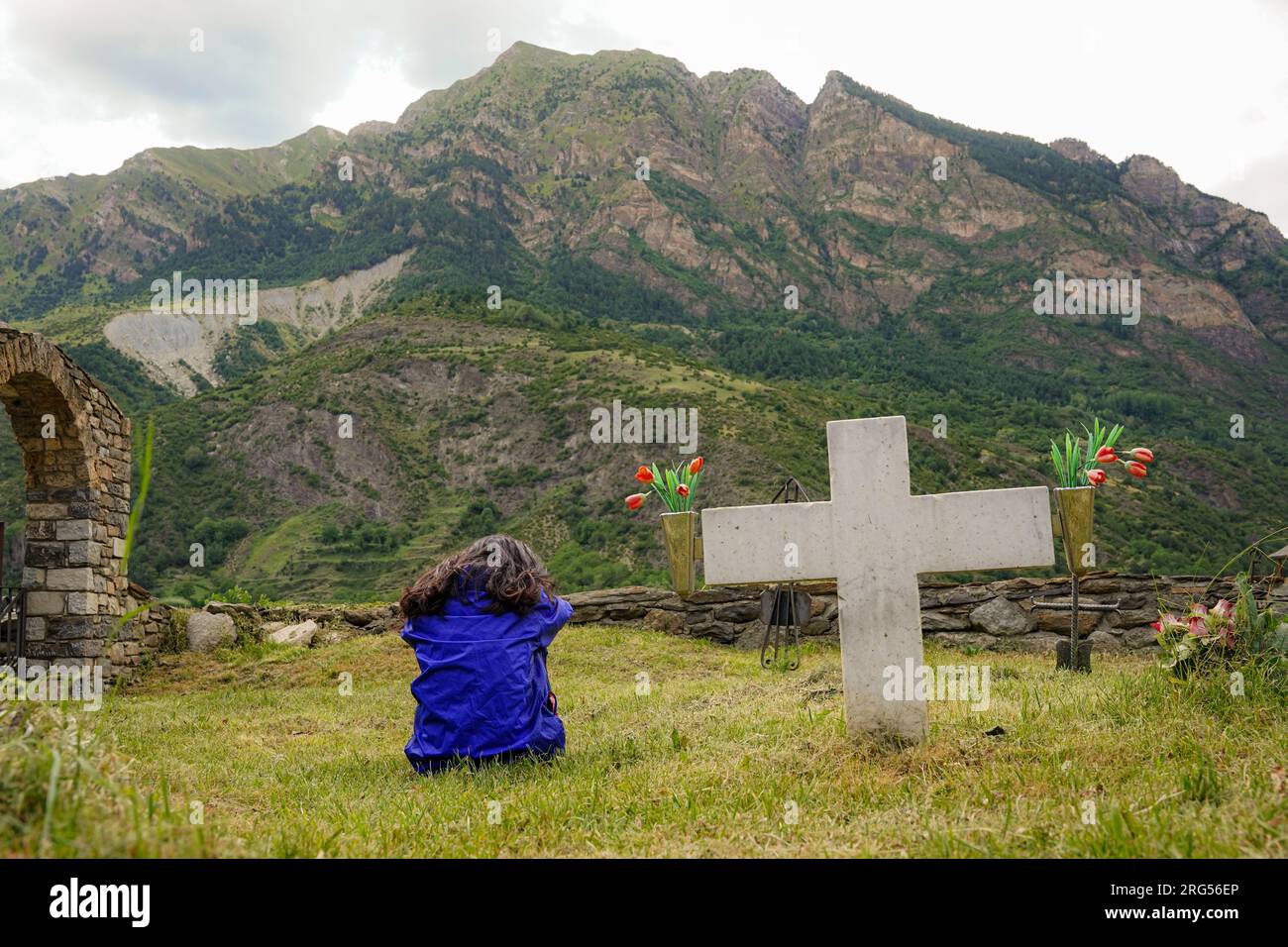 Young and mourning backwards woman at cemetery in the mountain. Sad ...