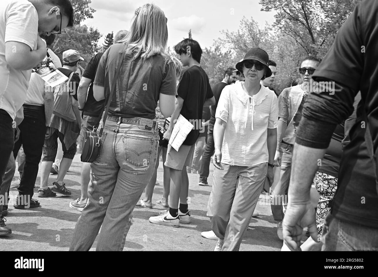 BLACK AND WHITE. 2023 Taste of Calgary food festival. A woman in a wide hat walks through the ...