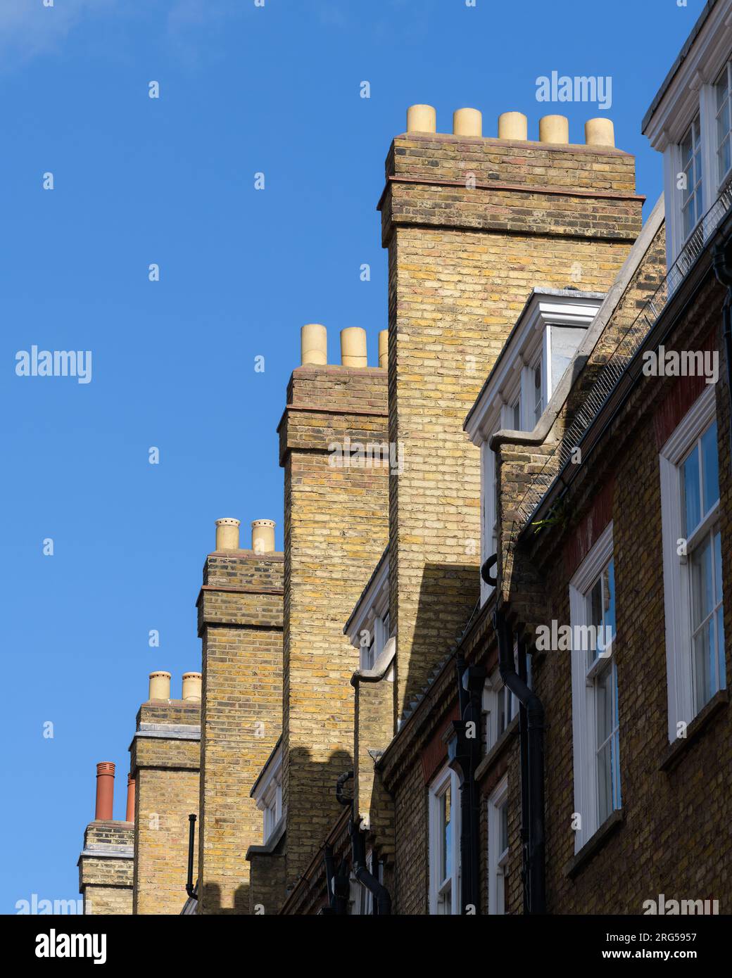 London, UK - July 31, 2023; Tall brick chimneys with pots on row of ...