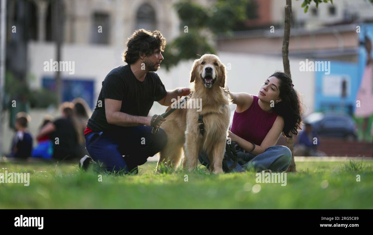 Candid couple sitting at park with their Dog on a leash. Young man and ...