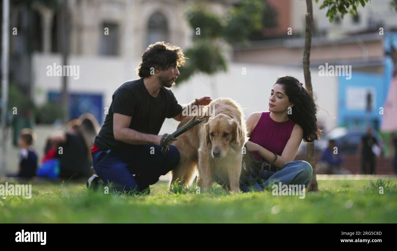 Candid couple sitting at park with their Dog on a leash. Young man and ...