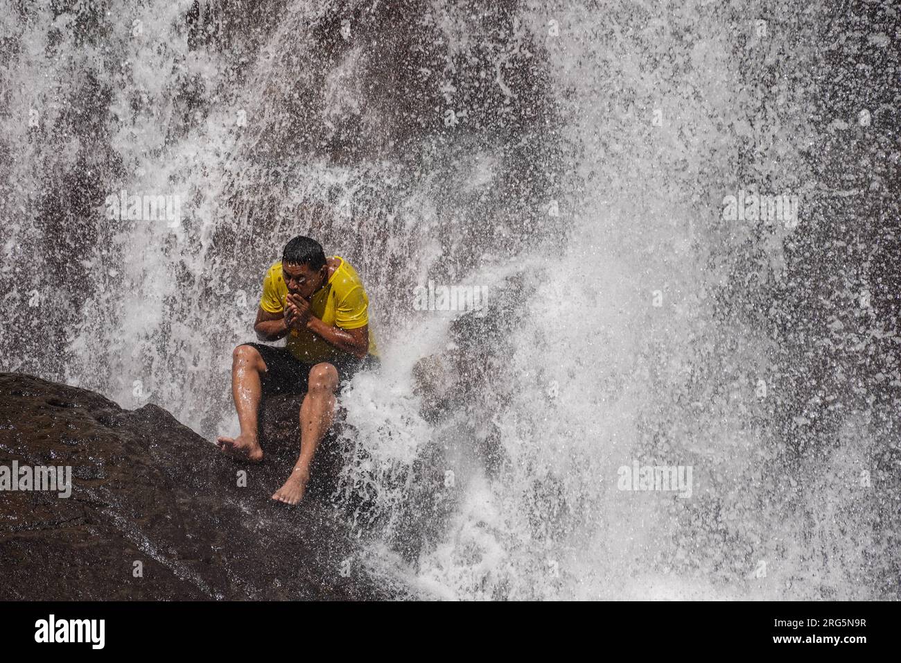 Arambala, El Salvador. 05th Aug, 2023. A man sits under a waterfall in ...