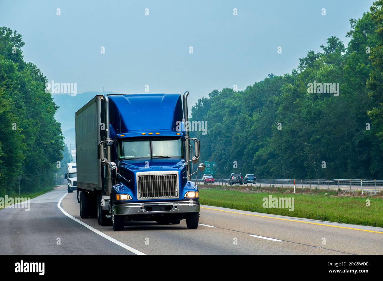 Horizontal shot of a blue tractor trailer rig cruising down an ...