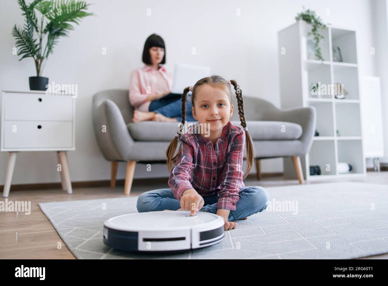 Tween girl starting tech gadget while mom typing emails Stock Photo - Alamy