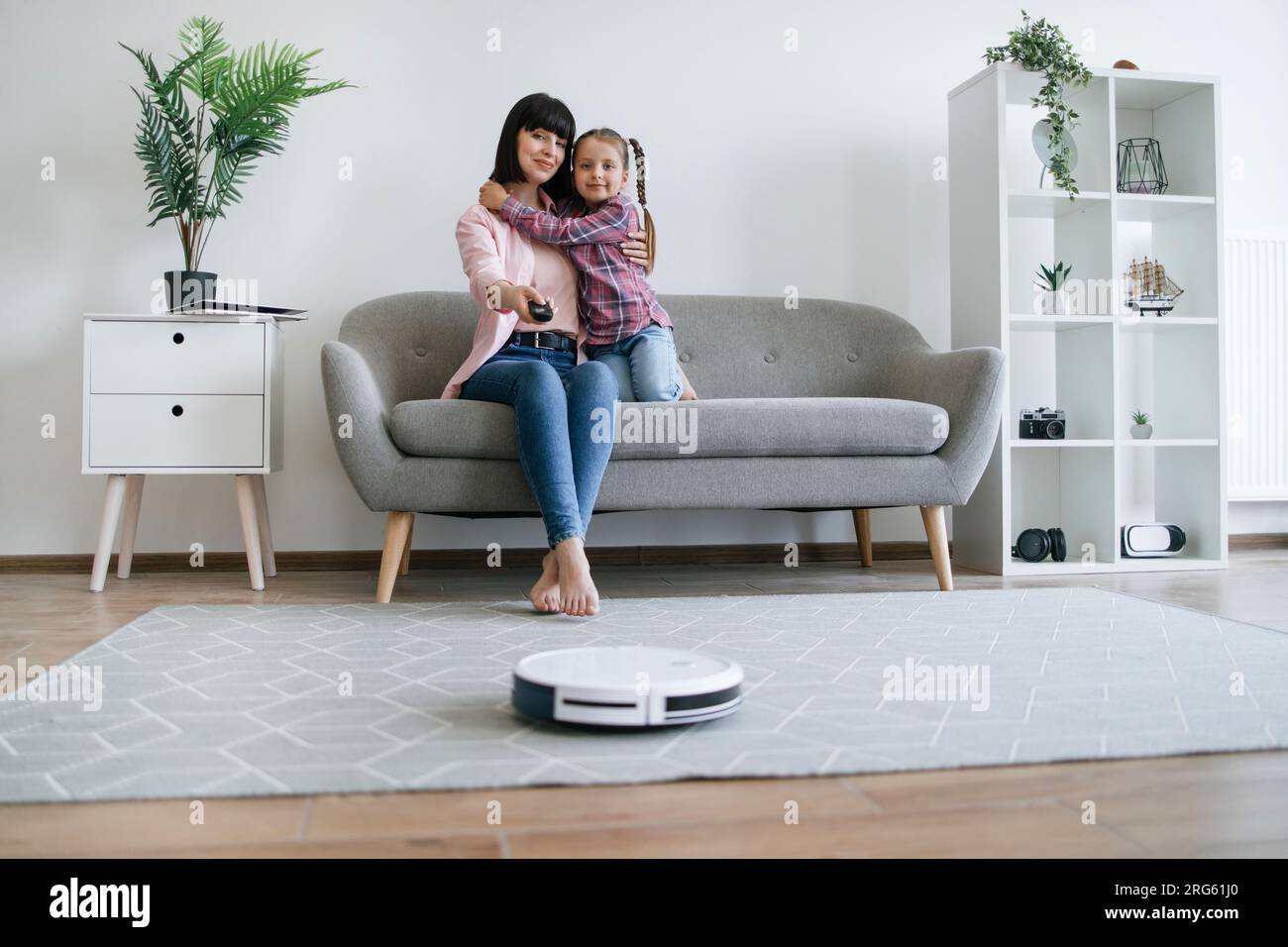 Mom hugging kid and turning on cleaning robot in living room Stock ...