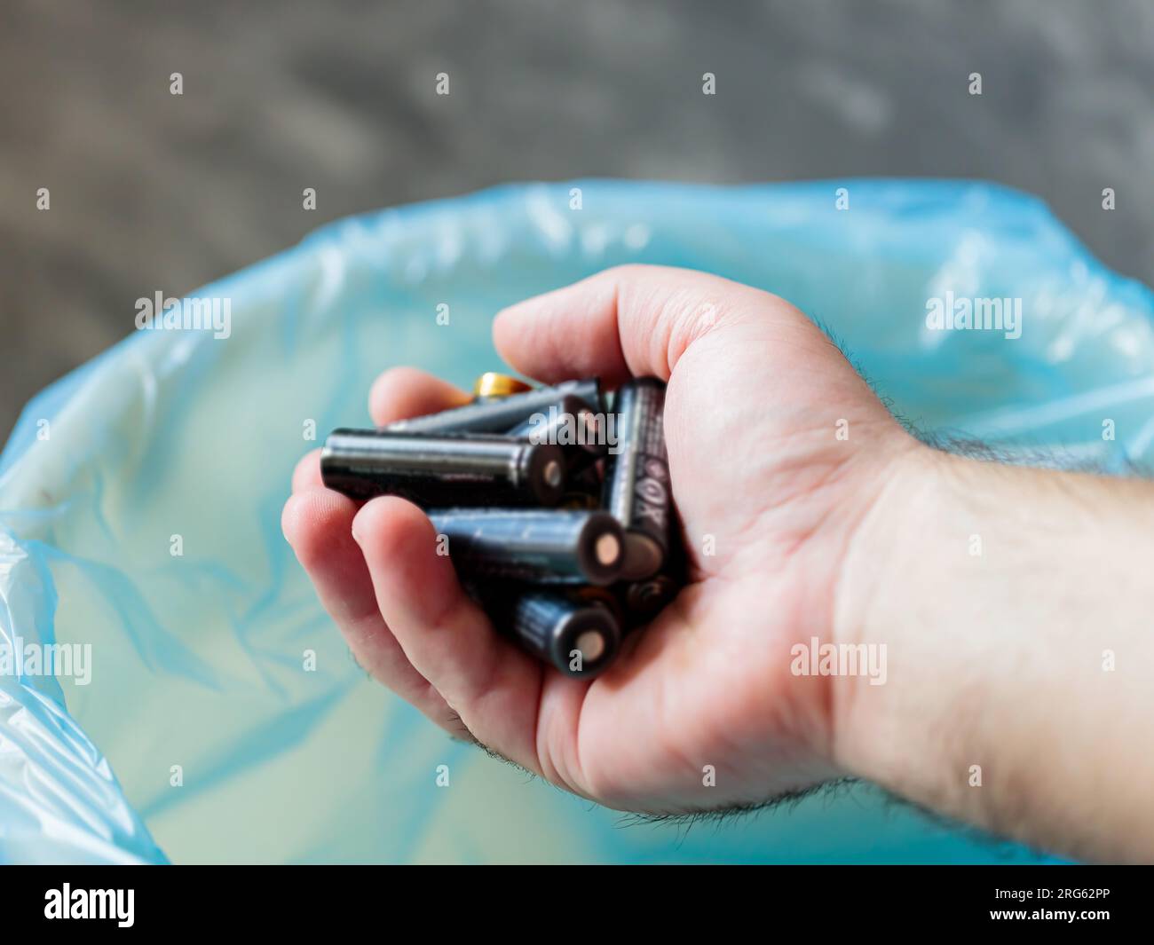 Eco-Conscious Disposal - Hand Holding Used Batteries Over Trash Can ...