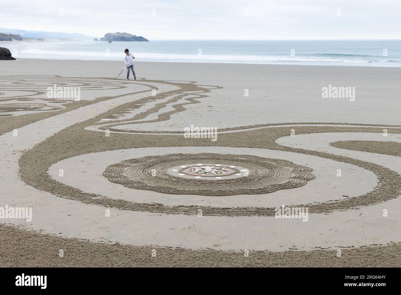 An artist working on a Circles in the Sand sand labyrinth on Face Rock ...