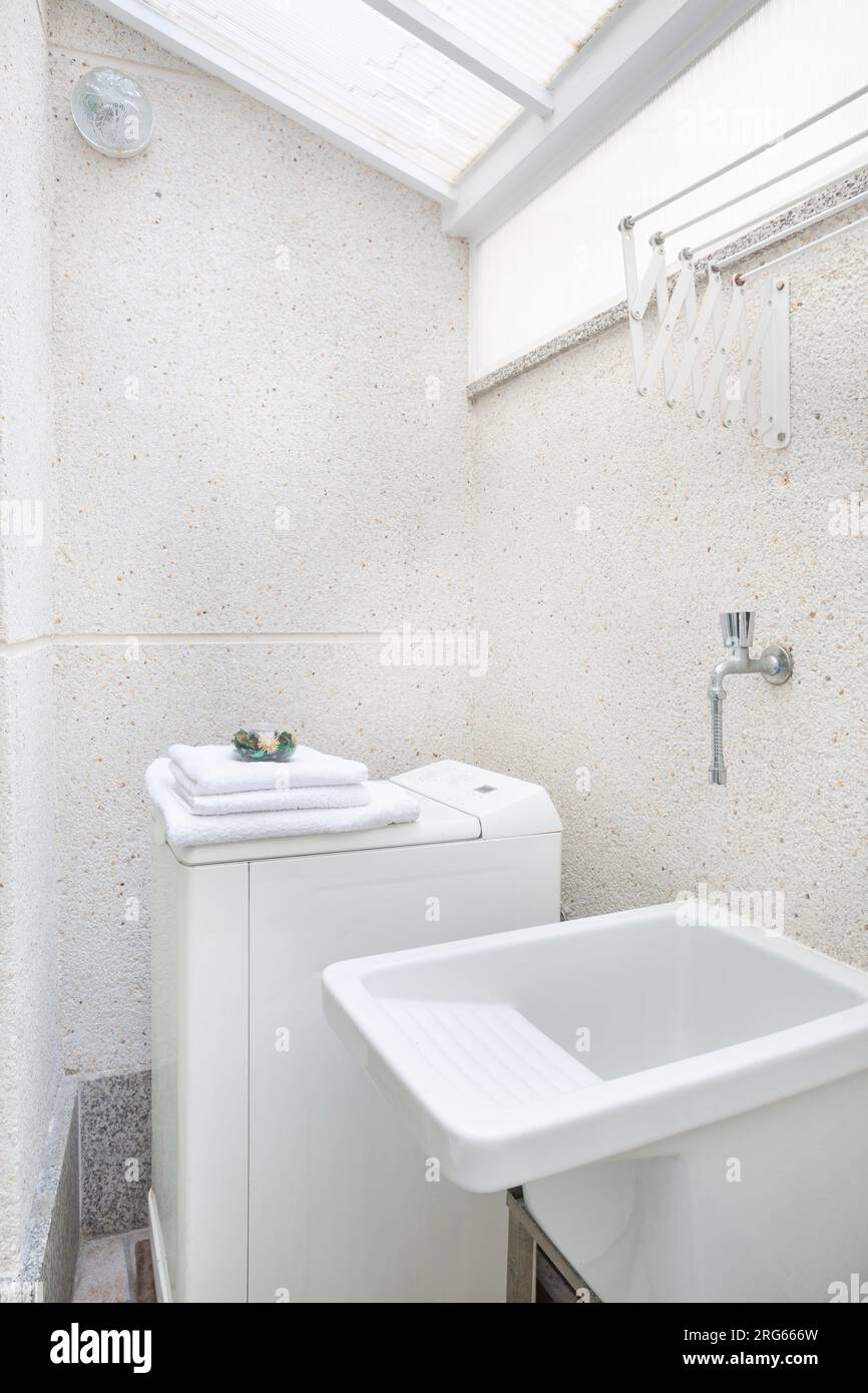 Laundry room with vertical washing machine, drying rack and sink, white ...