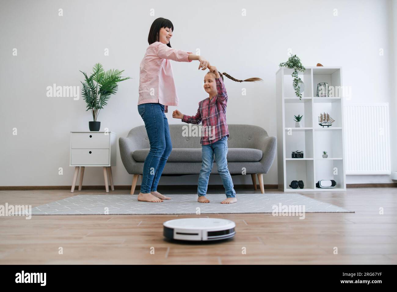 Kid spinning with mom while robot cleaner dealing with dirt Stock Photo ...