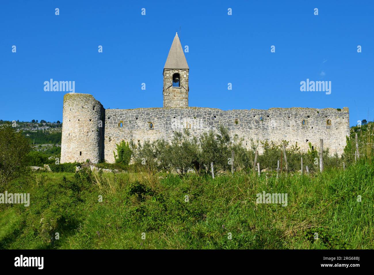 View of an old medieval church surrounded by a tall stone wall and a ...