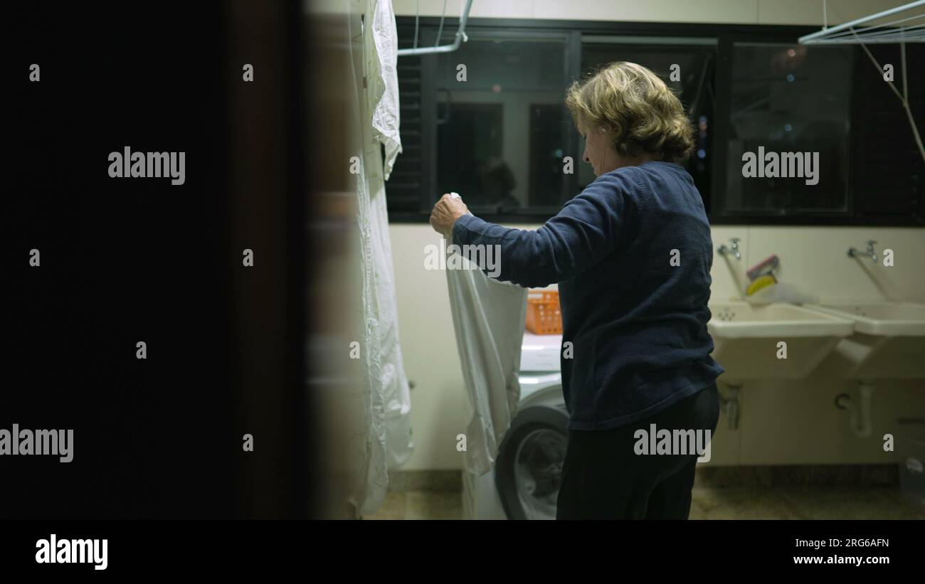 Candid older lady putting clothes to dry on laundry rack. Real life ...