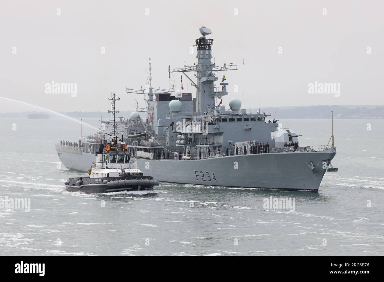 A tug sprays a jet of water to welcome the Royal Navy frigate HMS IRON ...