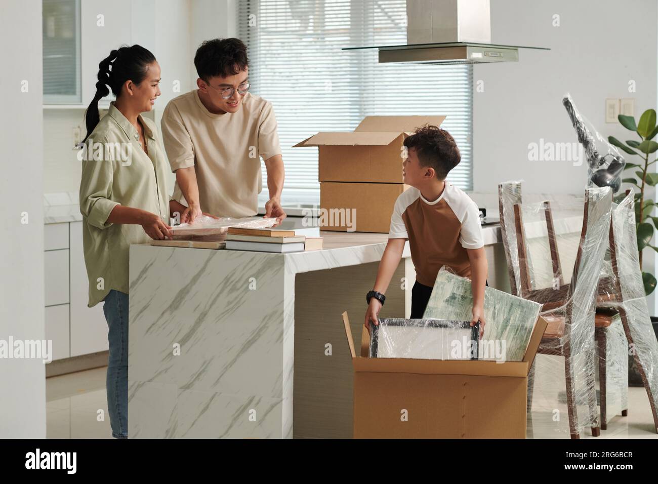 Family wrapping and packing pictures in cardboard boxes when moving out ...