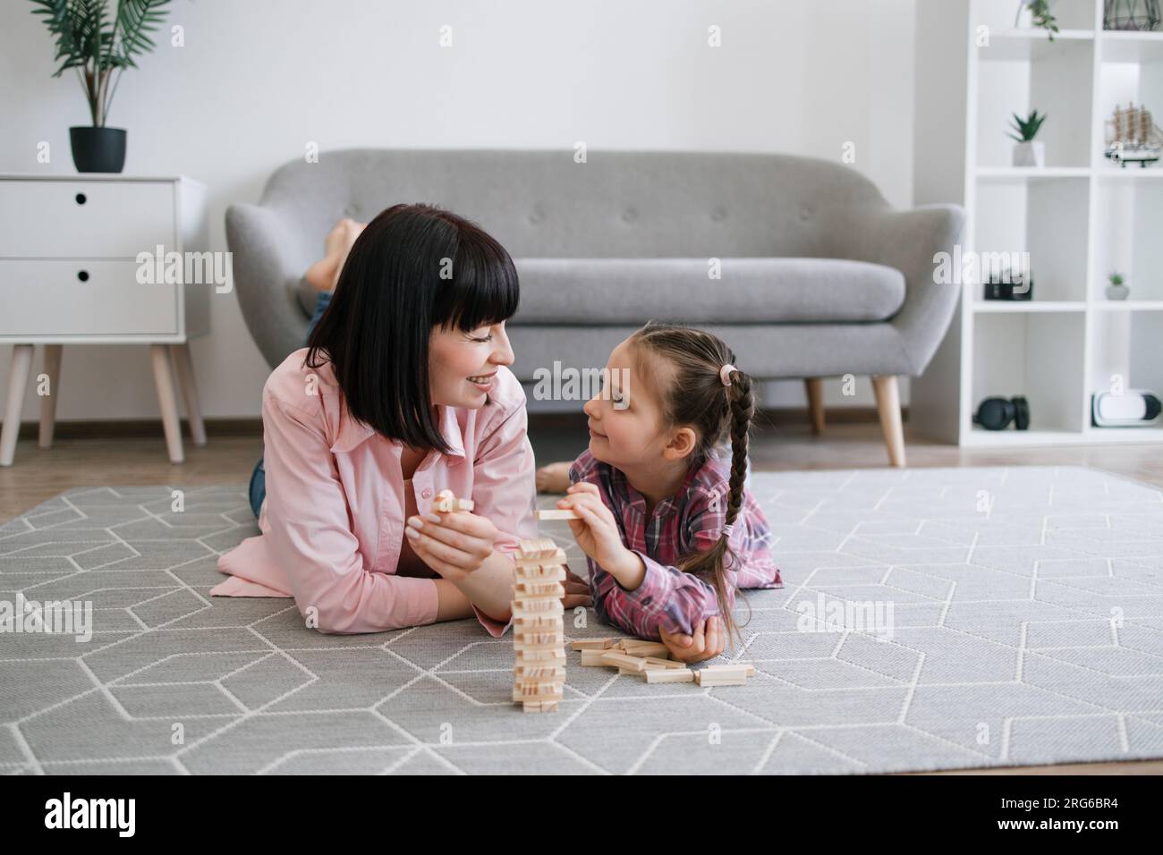 Female adult and kid stacking wooden blocks in toy building Stock Photo ...