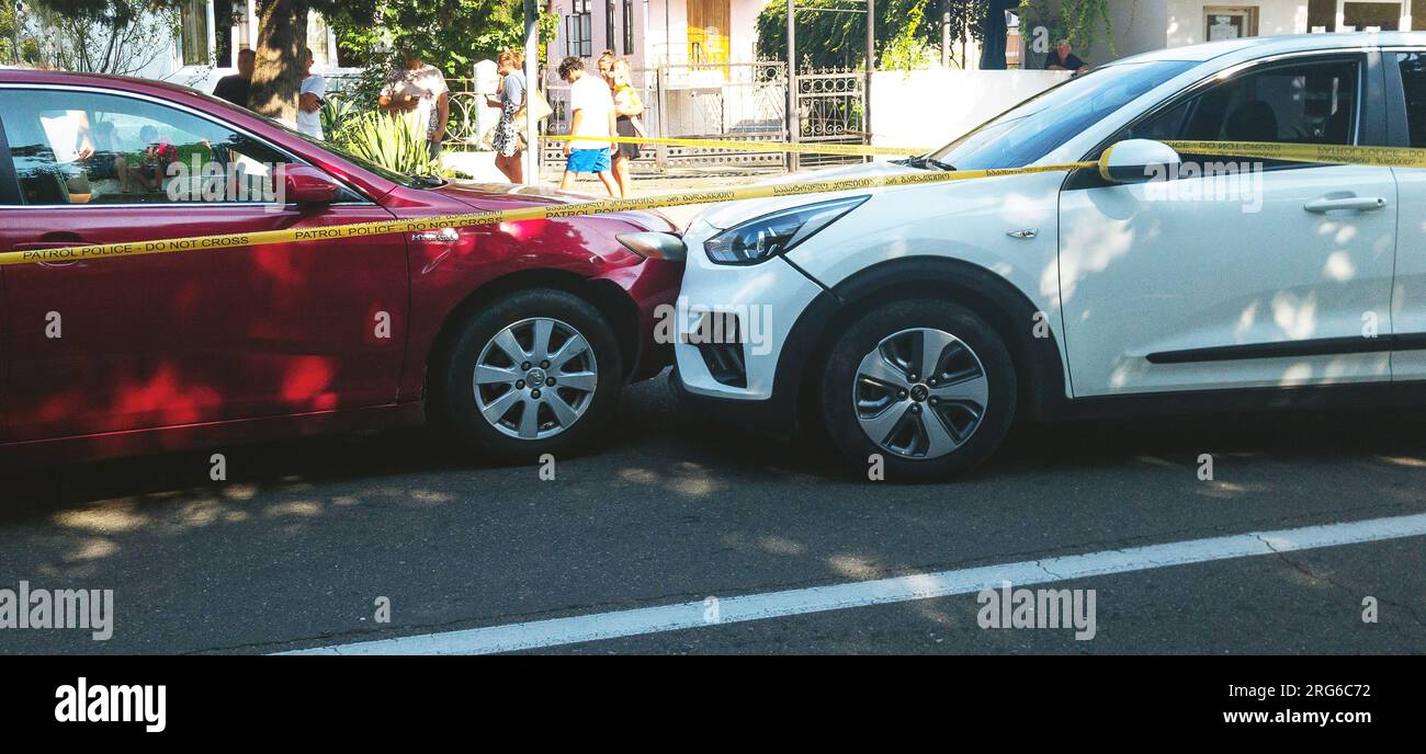 two frontal crashed black and white cars on street, black is in the ...