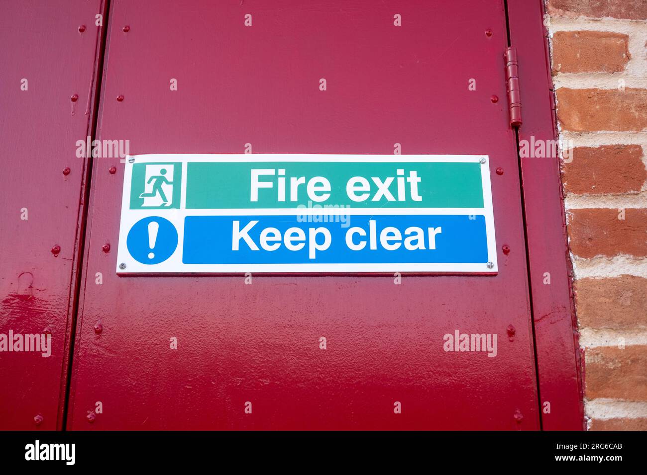 Fire Exit - Keep Clear Sign against a red door Stock Photo - Alamy