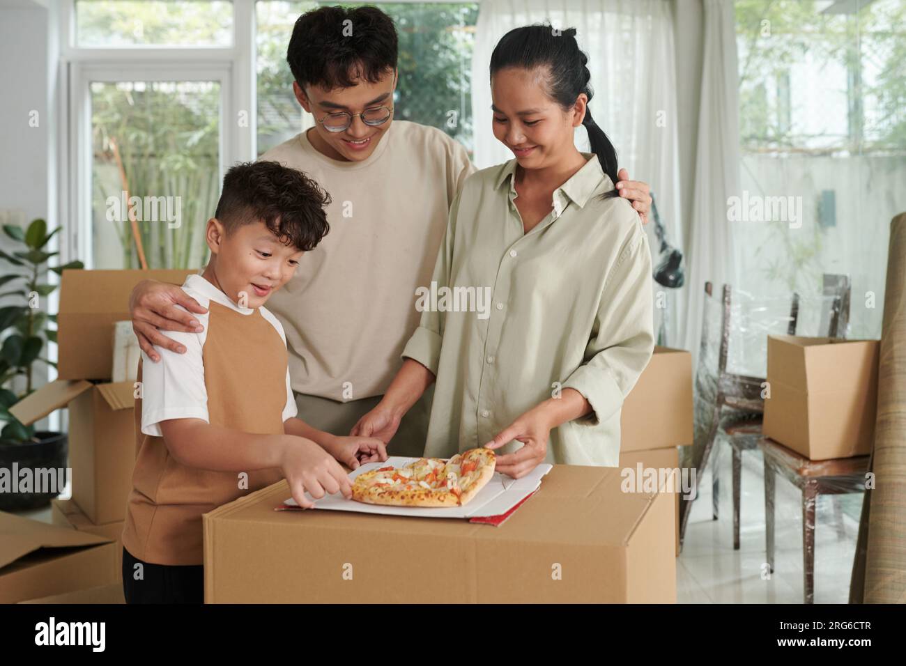 Cheertful family eating pizza after finishing packing belongings in ...