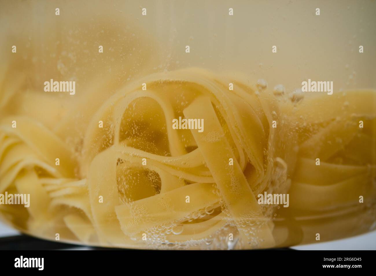 Closeup view of fettuccine pasta into boiling water in a transparent ...