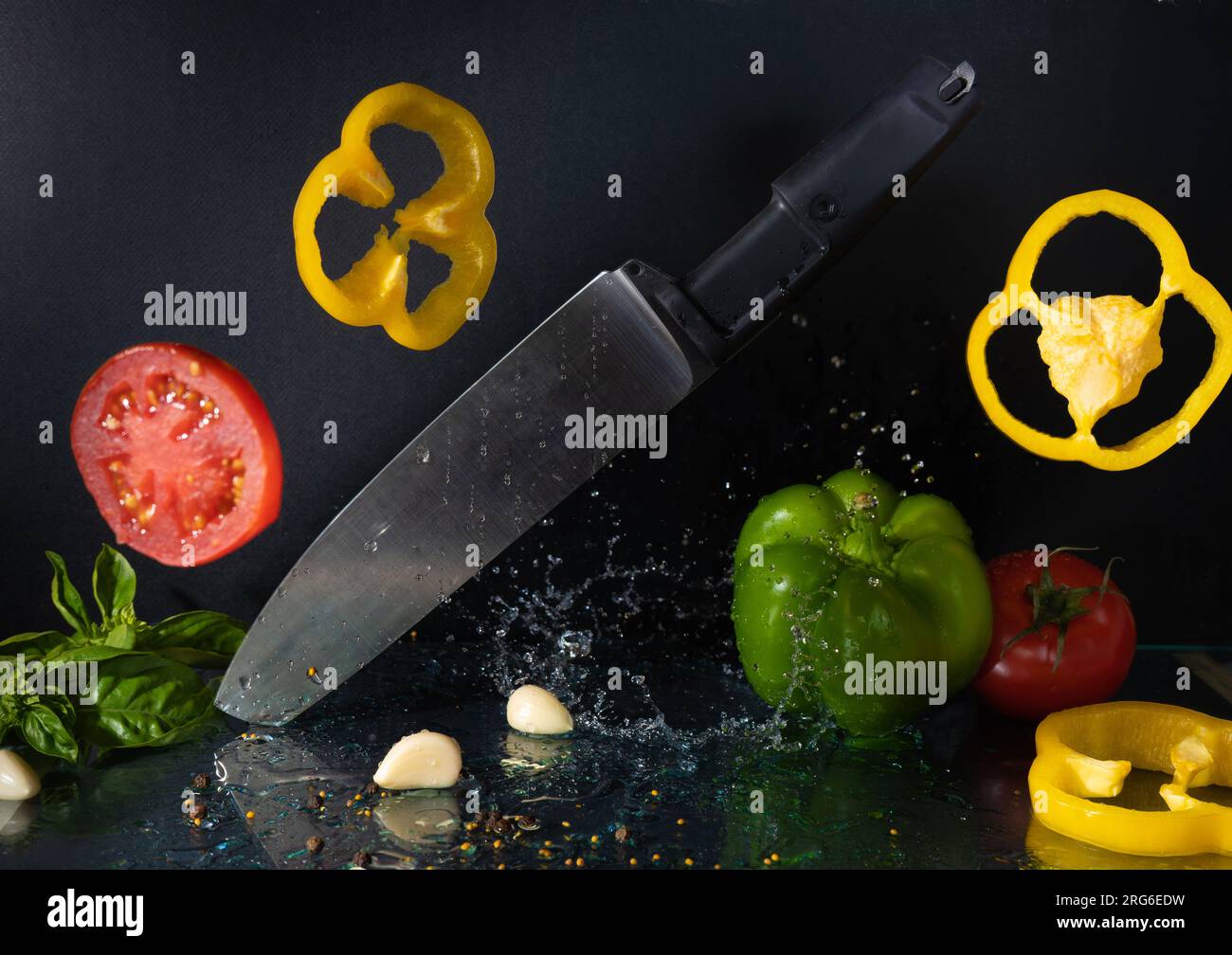 Kitchen knife and bright vegetable pieces food levitation on dark black ...